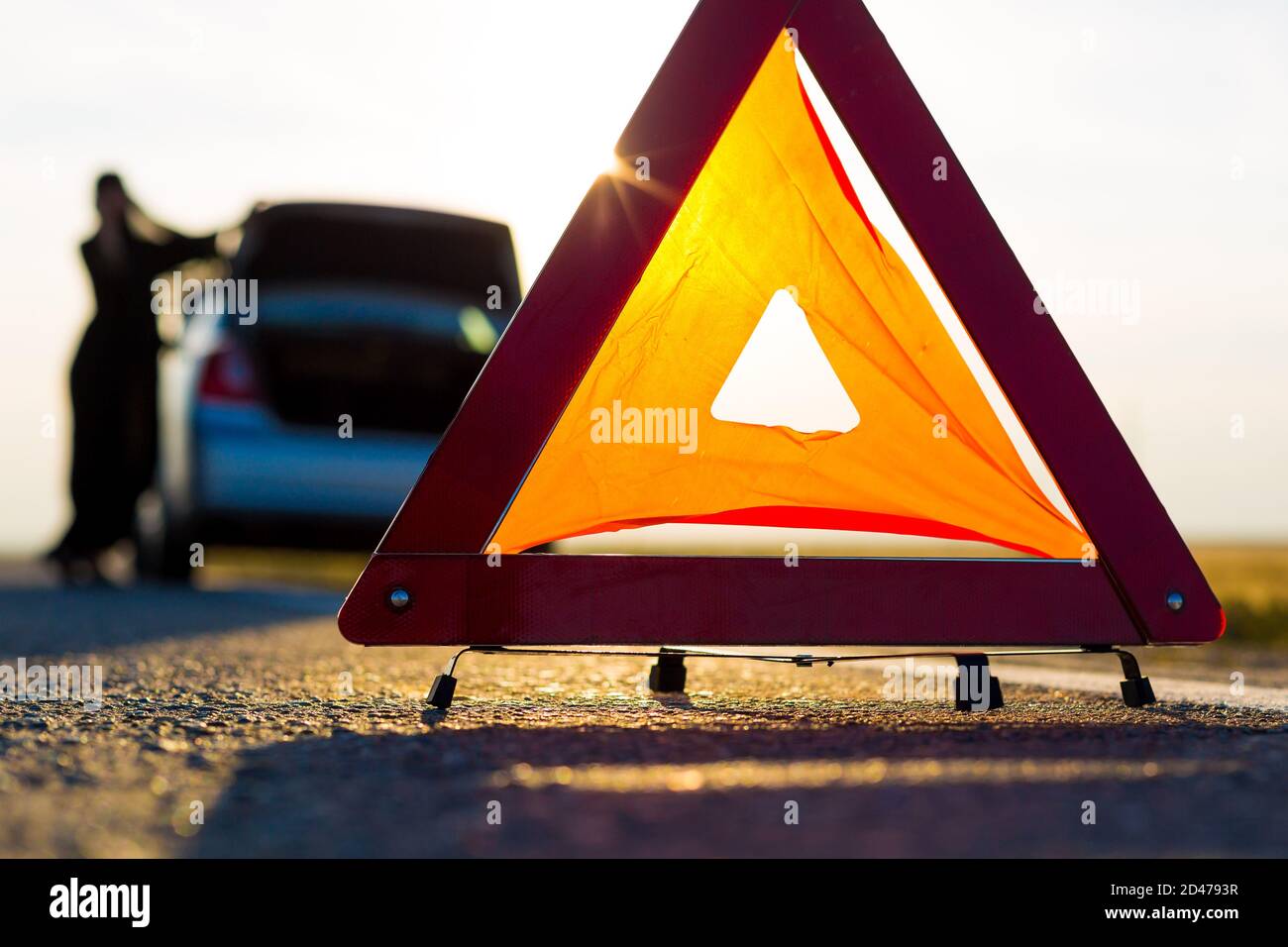 Emergency triangle sign set on road near broken car with islamic woman ...