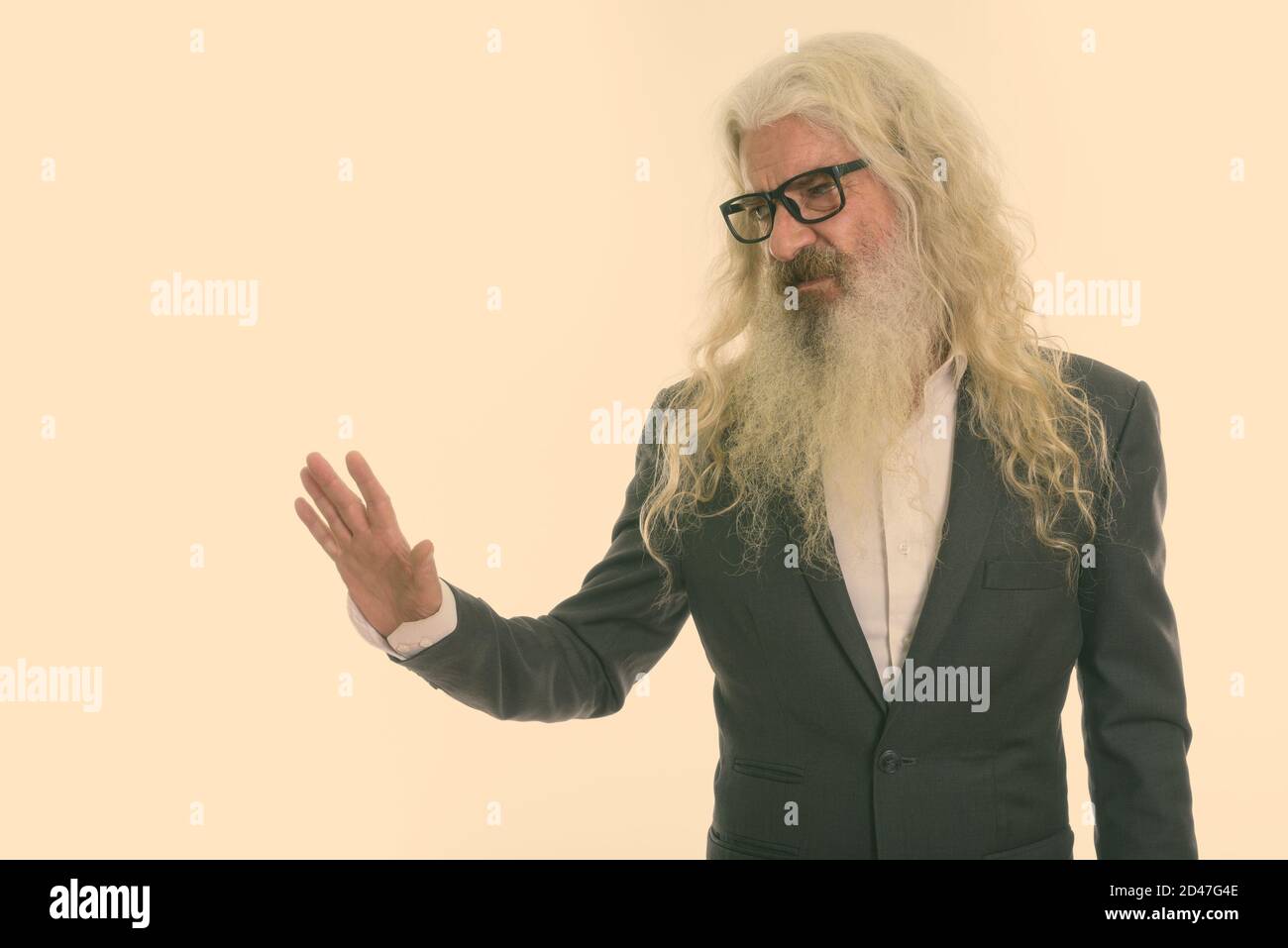 Studio shot of senior bearded businessman looking disgusted while ...