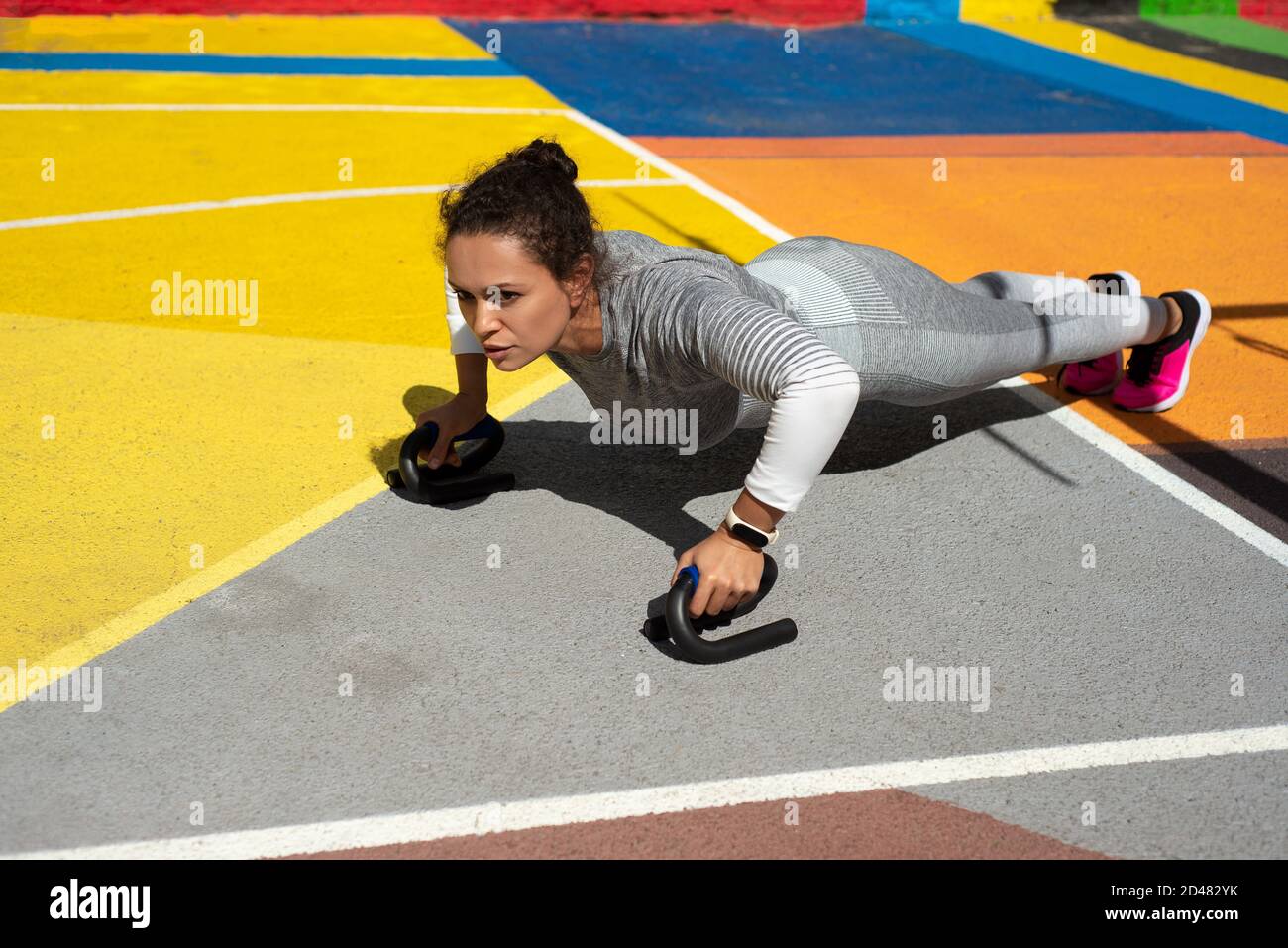 The young woman in gray tracksuit doing push-ups using palm rests Stock ...
