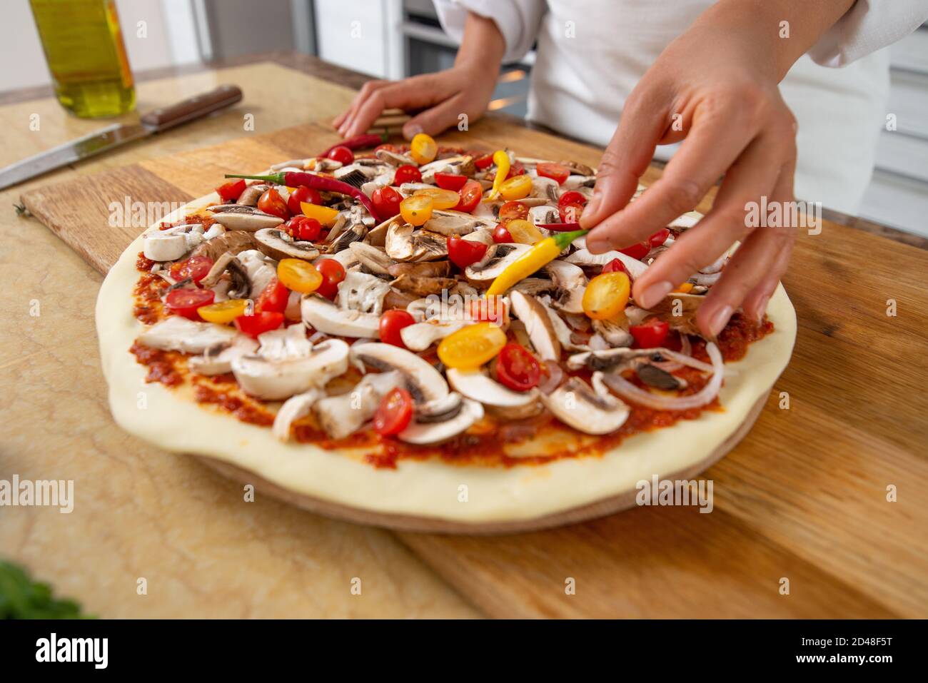 The view of the hands of the chef adding hot peppers to the pizza ...