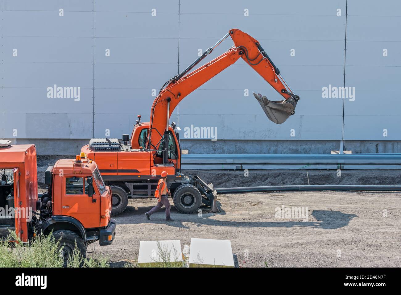 Foreman and large equipment, excavator and truck on site during ...