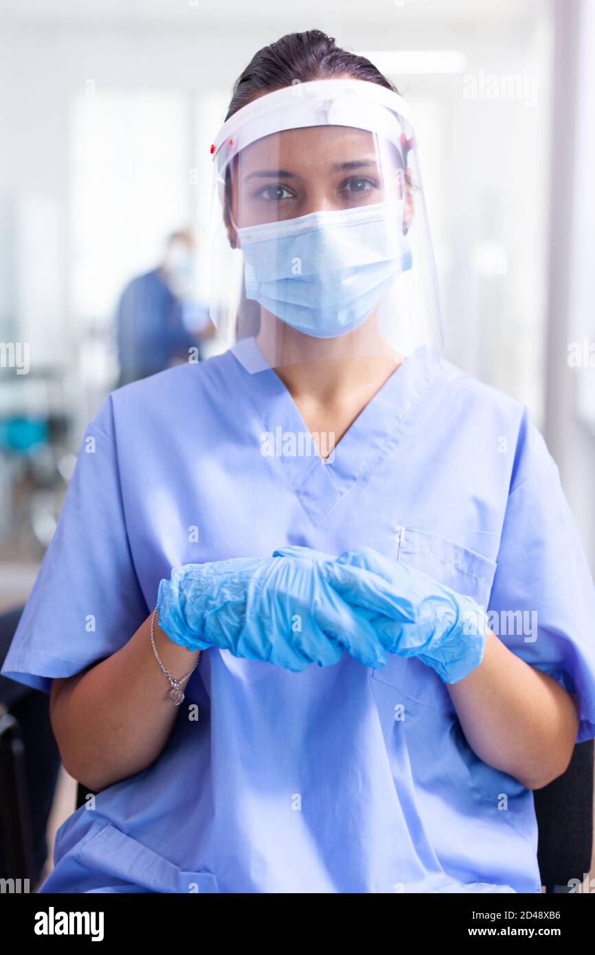 Medical assistant with visor and face mask tired in hospital waiting ...