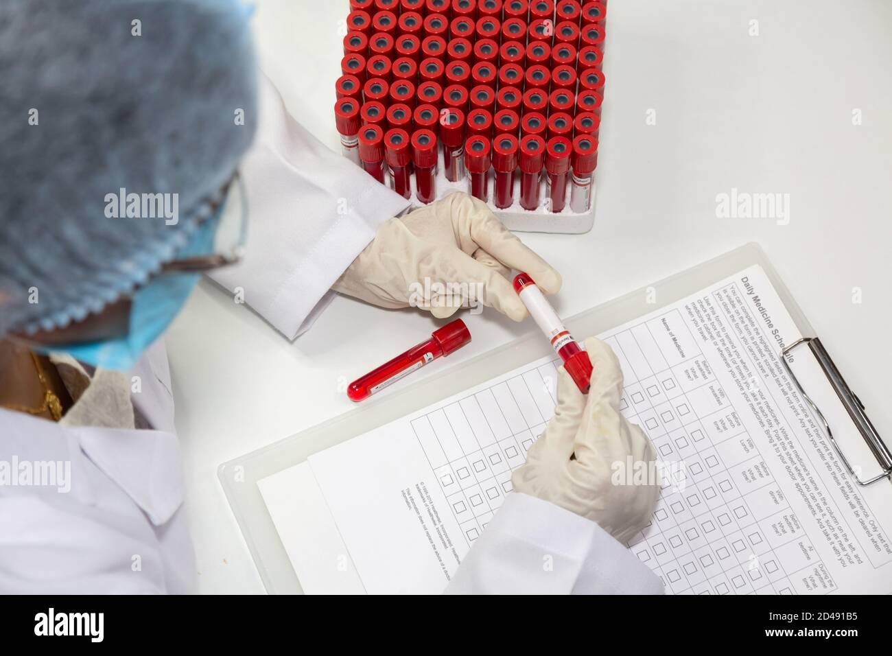 Indian doctor examine patient blood test sample vials while preparing ...