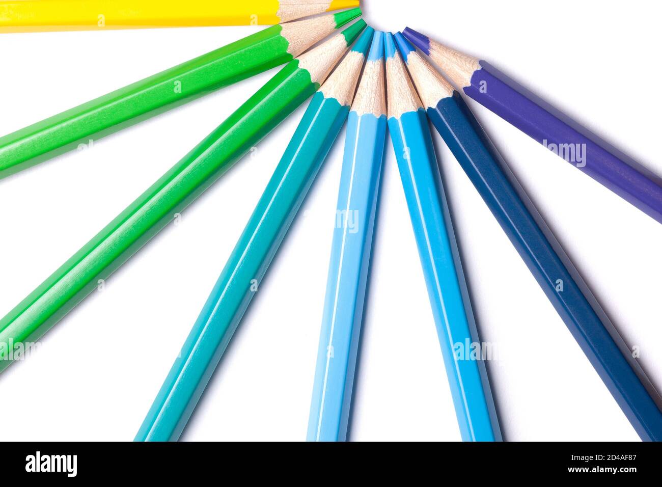 a semicircle of blue and green sharp pencils on a white background ...