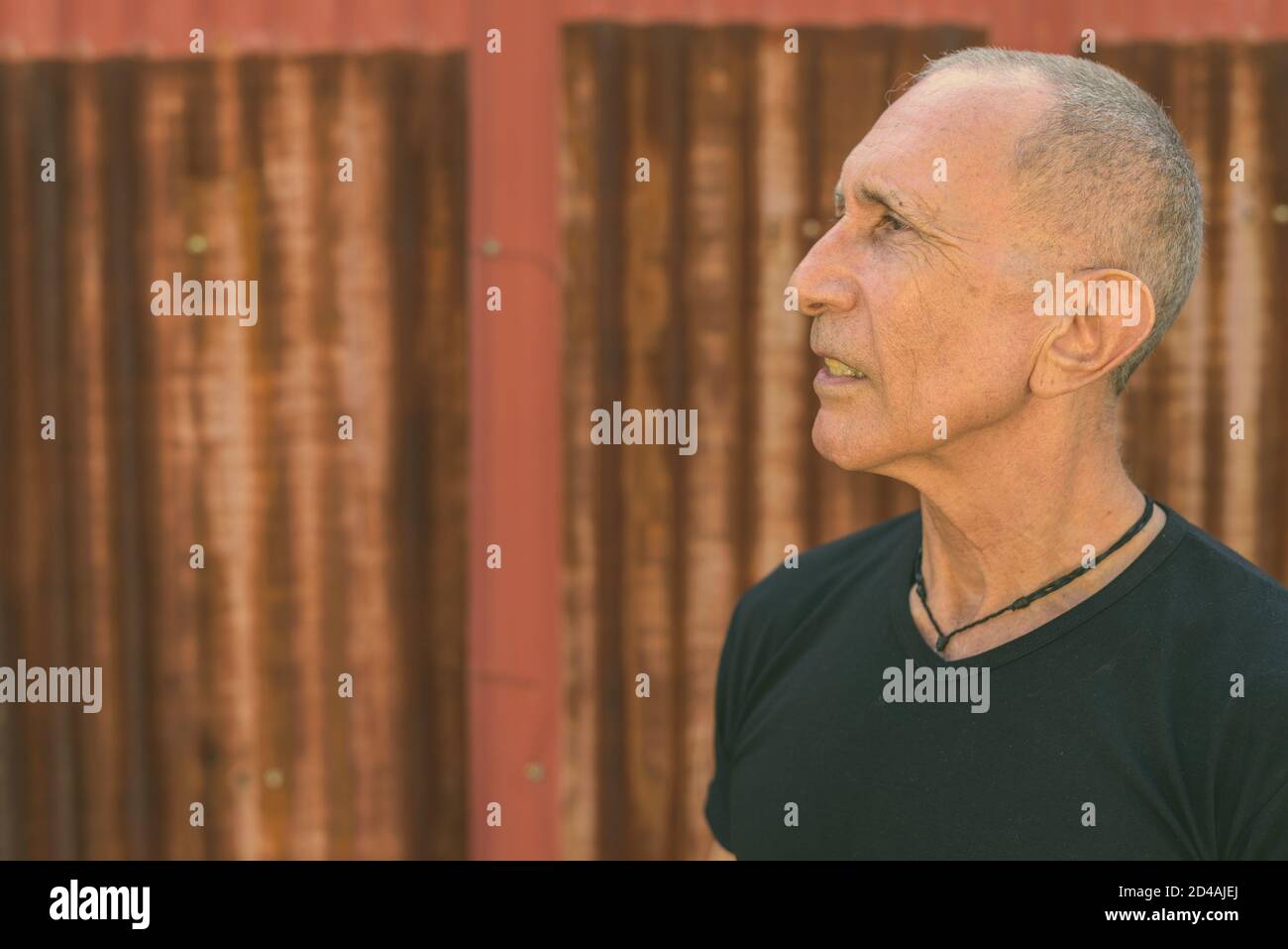 Close up profile view of bald senior man thinking against old rusty ...