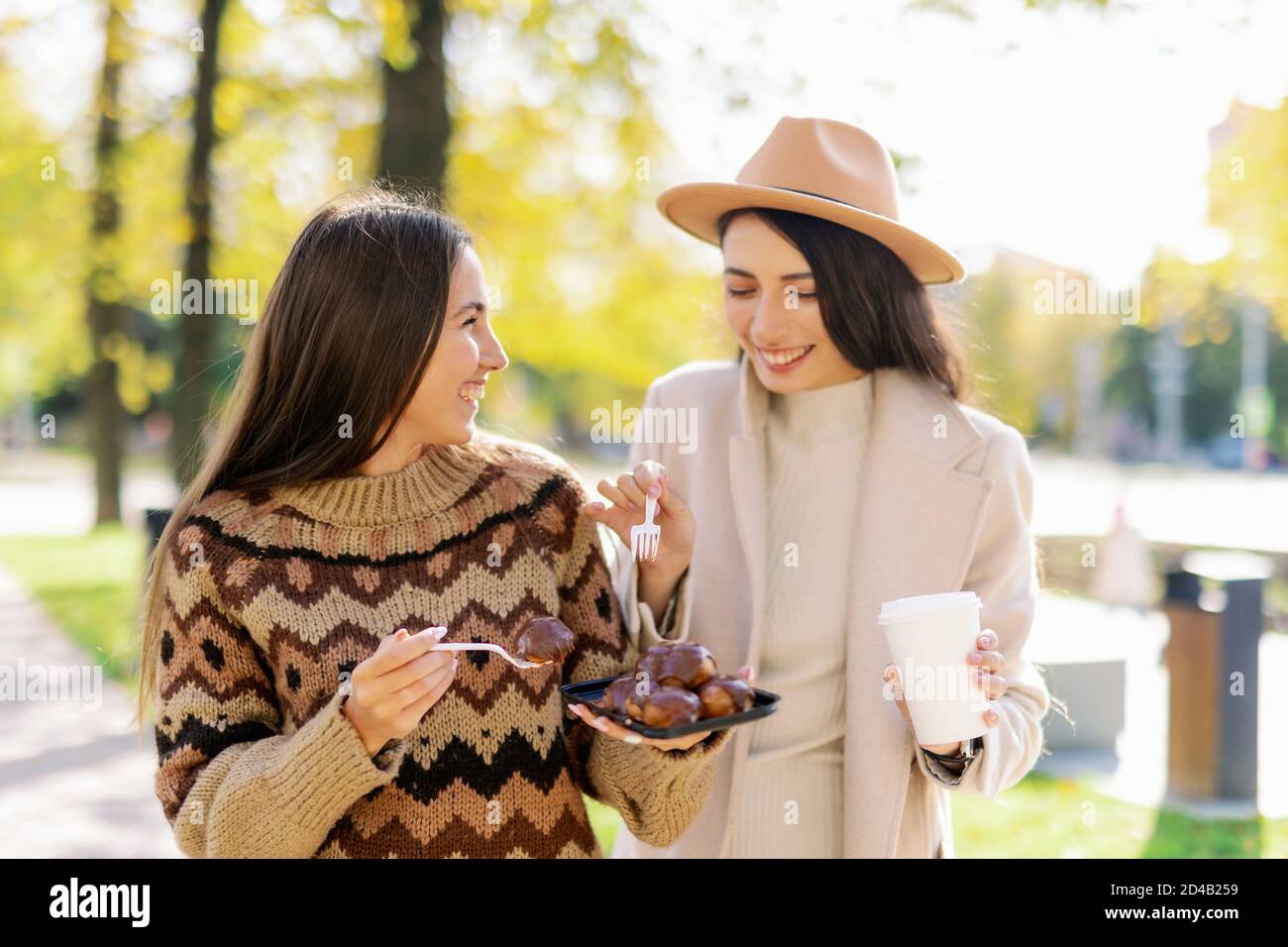 Cupcakes - two woman's sitting eating cupcake in outdoor autumn Park ...
