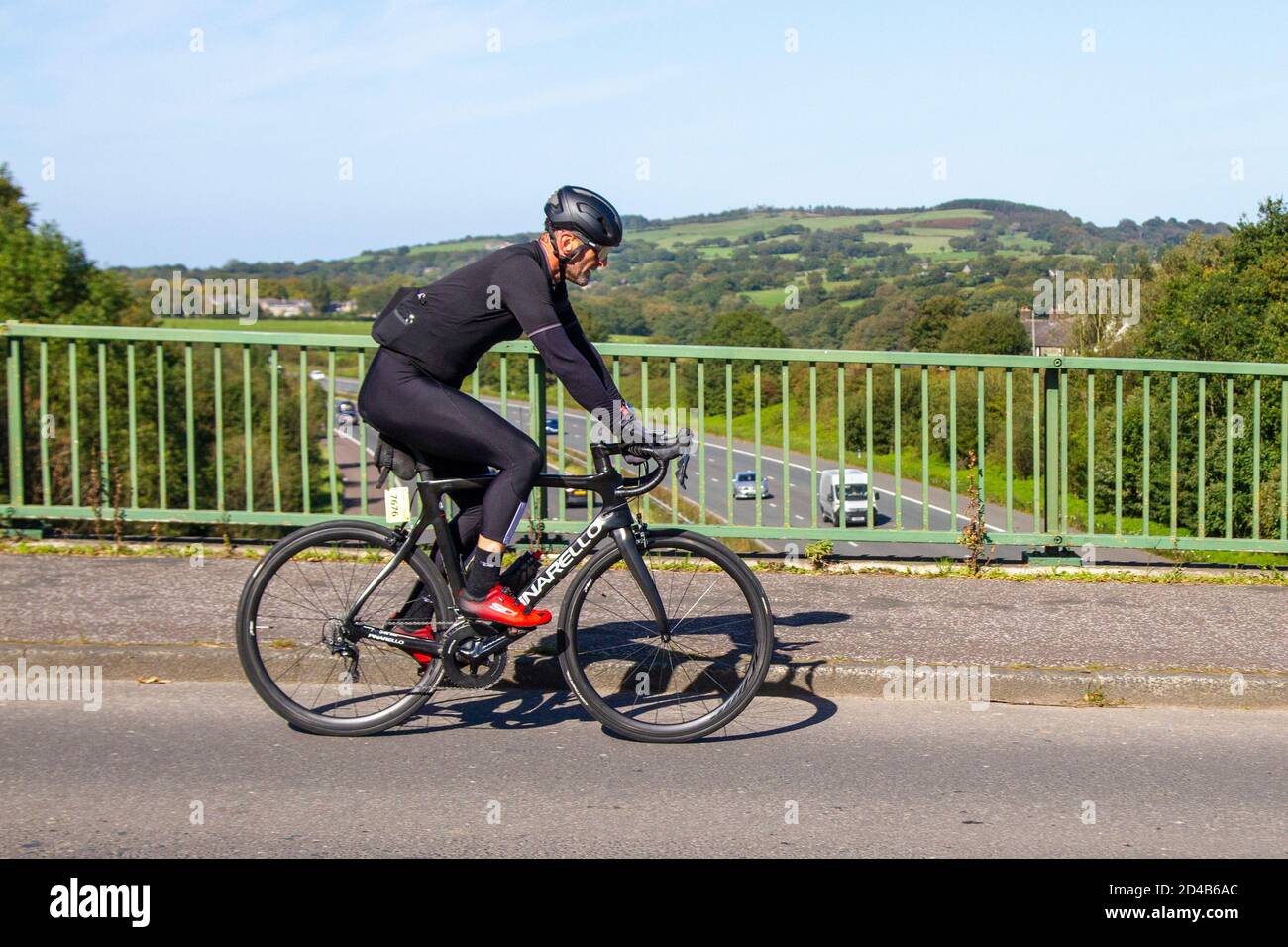 Male cyclist riding black Pinarello sports road bike on countryside ...