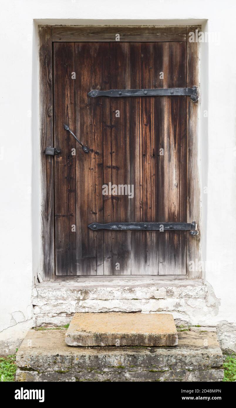 Old brown wooden door in a white wall. Vertical background photo ...