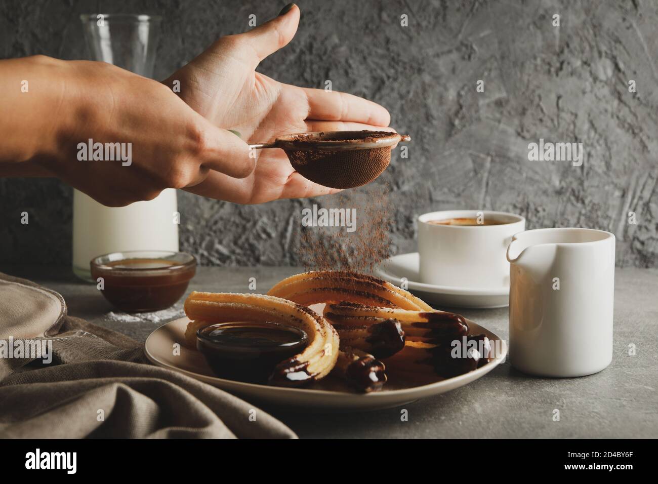 Woman sprinkle chocolate powder to sweet churros Stock Photo - Alamy