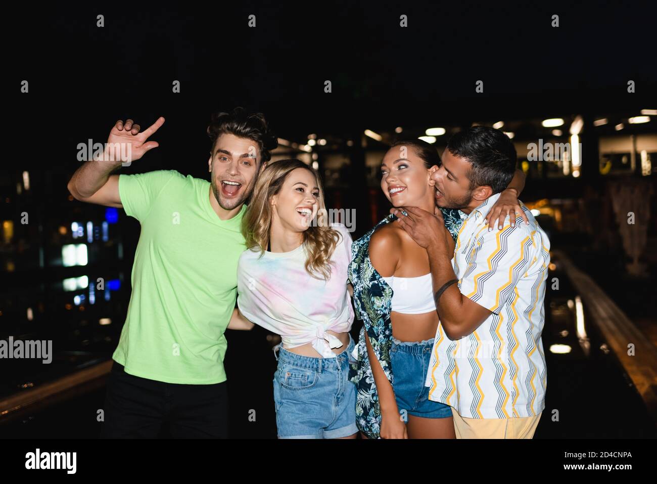 Young couples embracing near swimming pool at night Stock Photo - Alamy