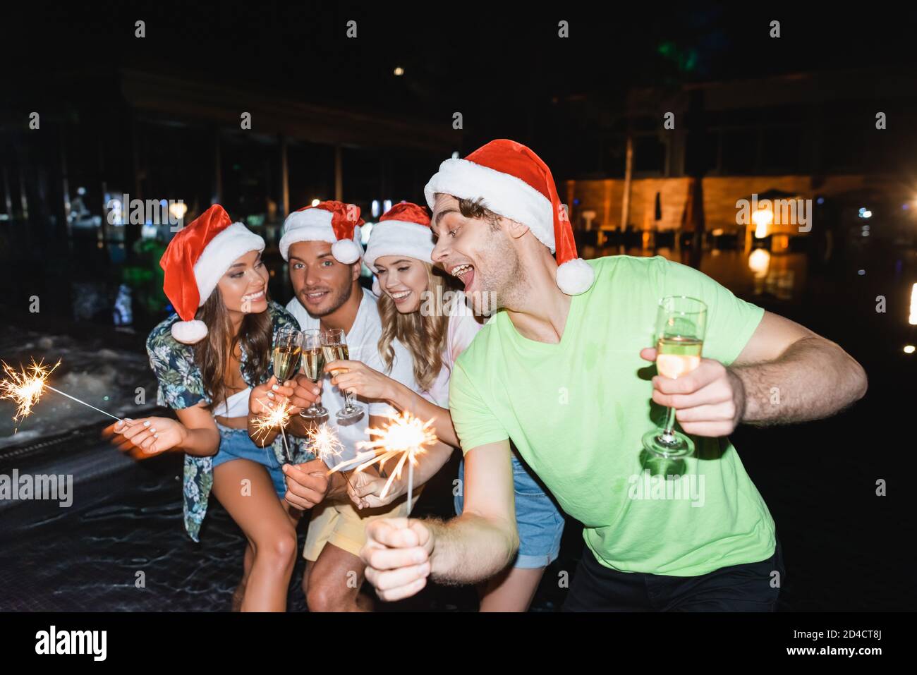 Selective focus of friends with sparklers clinking with champagne near ...