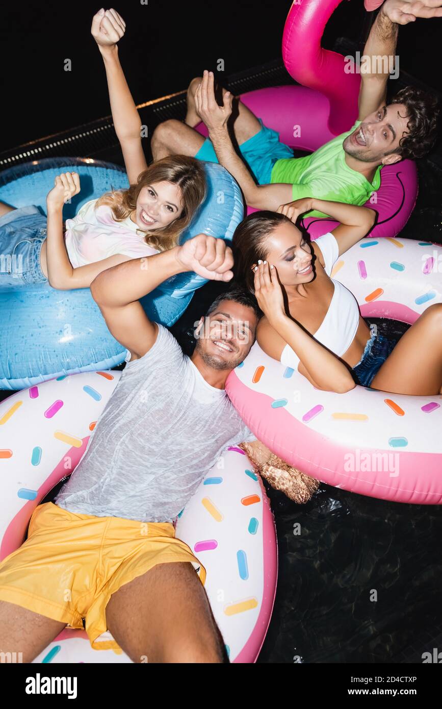 Friends looking at camera in swimming pool at night Stock Photo - Alamy
