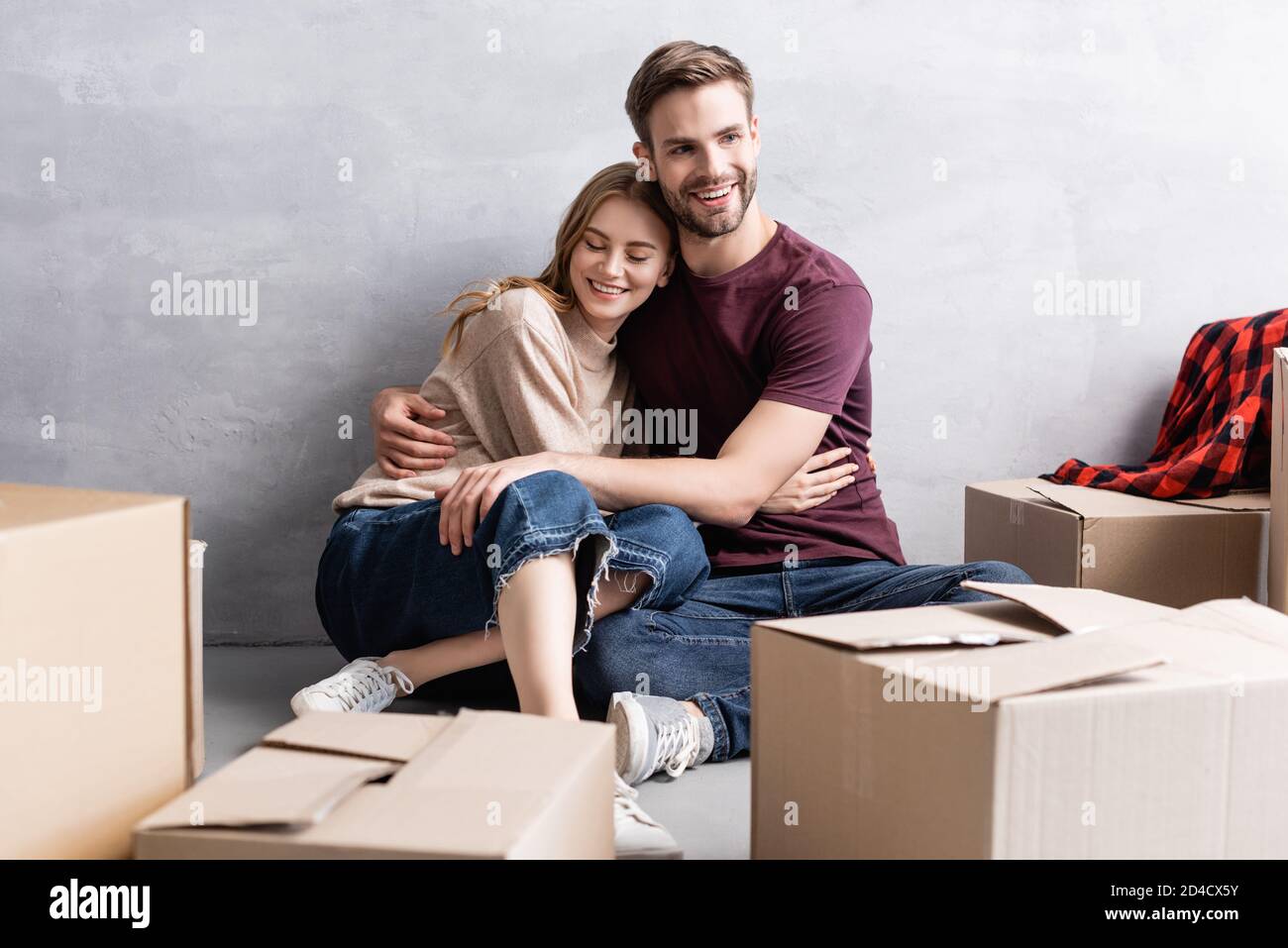 pleased man sitting of floor and hugging woman near boxes Stock Photo ...