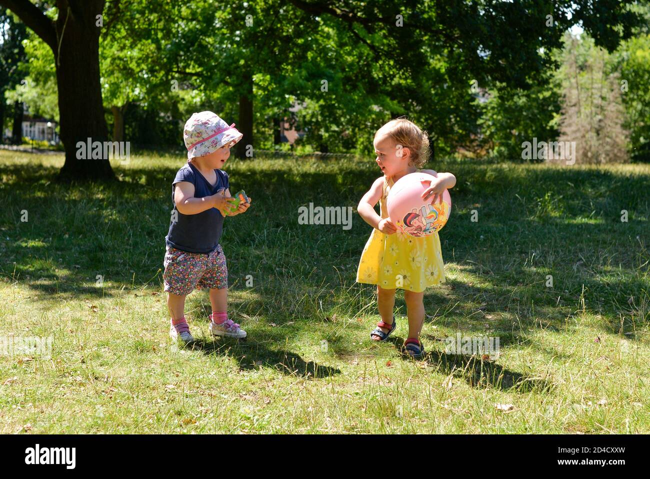 Two small children playing in a park with a ball Stock Photo - Alamy