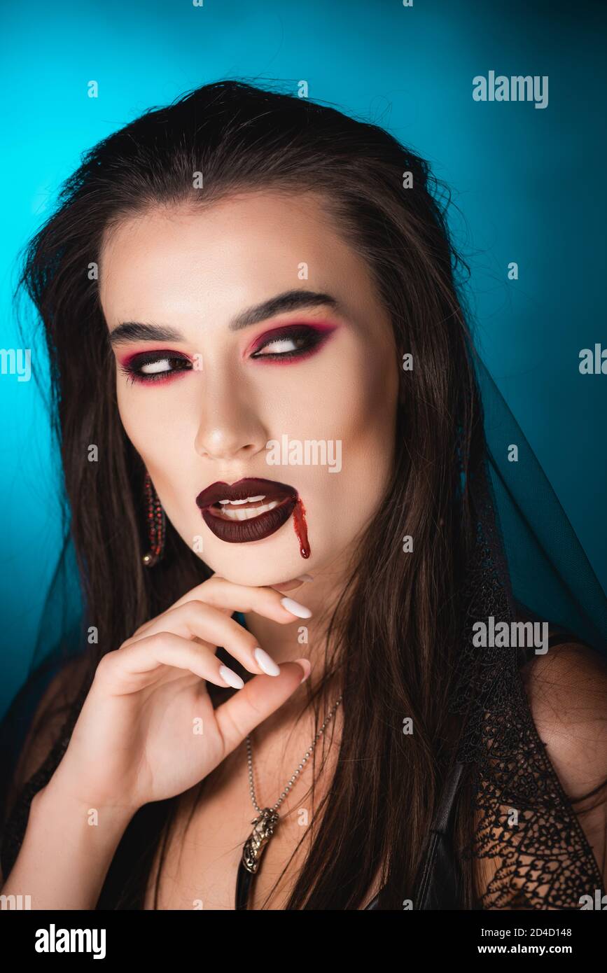 scary woman with blood on face looking away on blue Stock Photo - Alamy