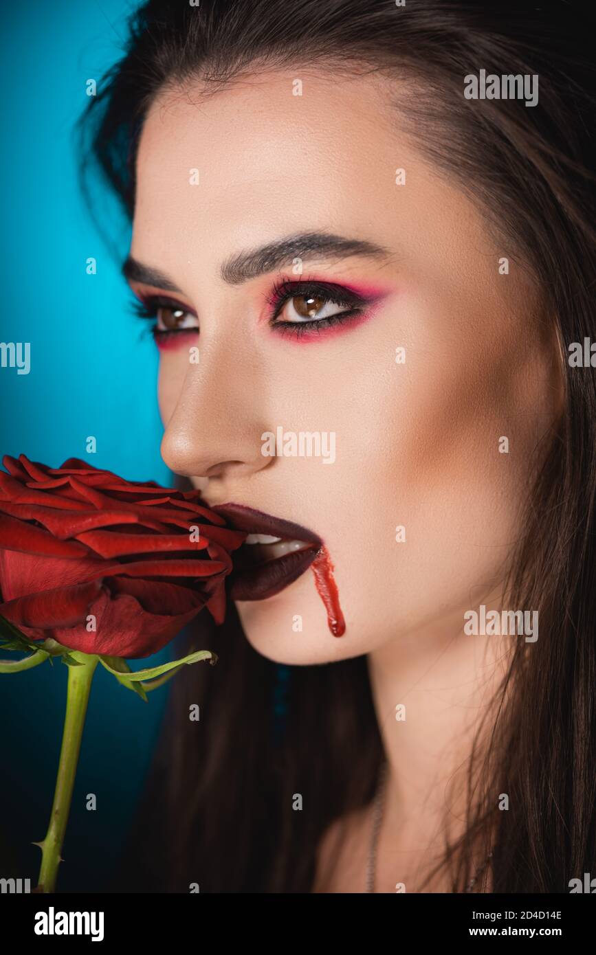 young creepy woman with blood on face near red rose on blue Stock Photo ...
