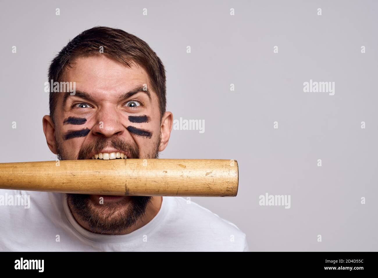 Aggressive man with a baseball bat in his hands on a gray background ...