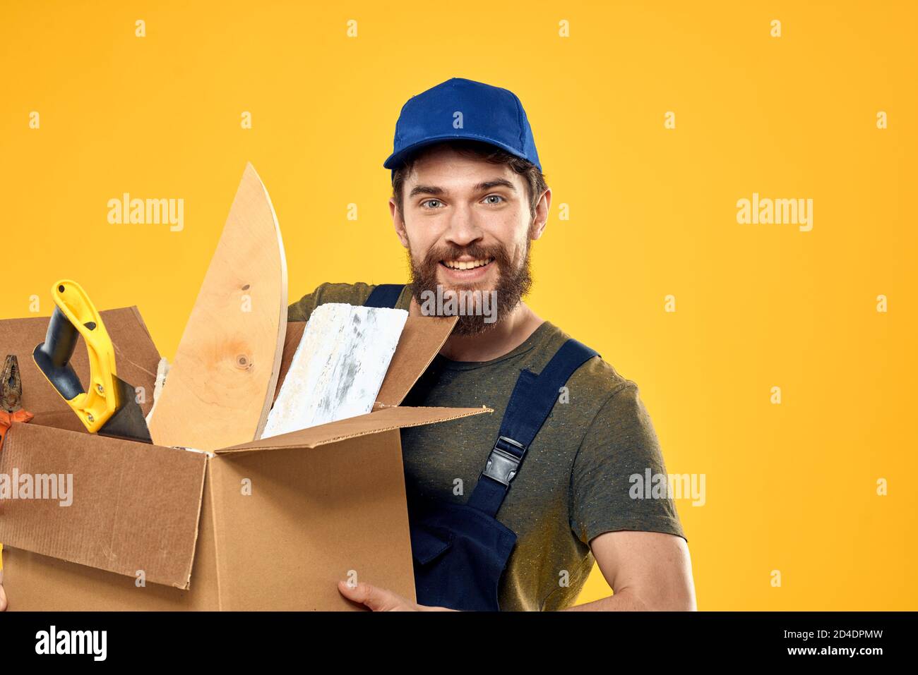 A man in a working form a box with loading tools yellow background ...