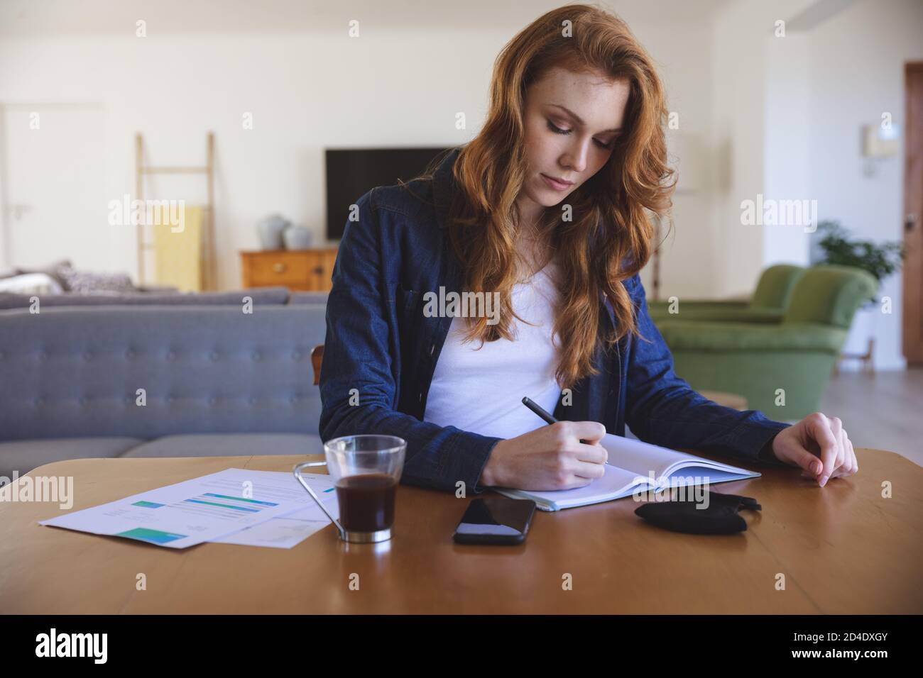 Woman taking notes while sitting on her desk at home Stock Photo - Alamy