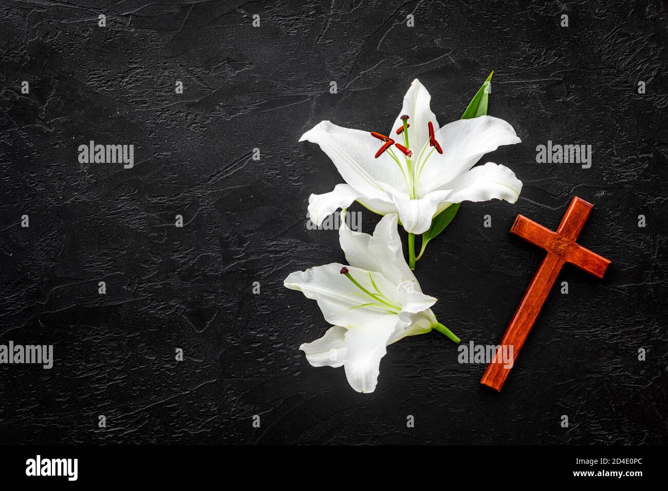 Funeral lily flowers with cross on dark stone background. Mourning ...