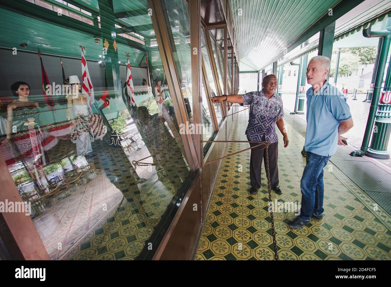 Tour guide explaining to a tourist about traditional clothes of Mataram ...