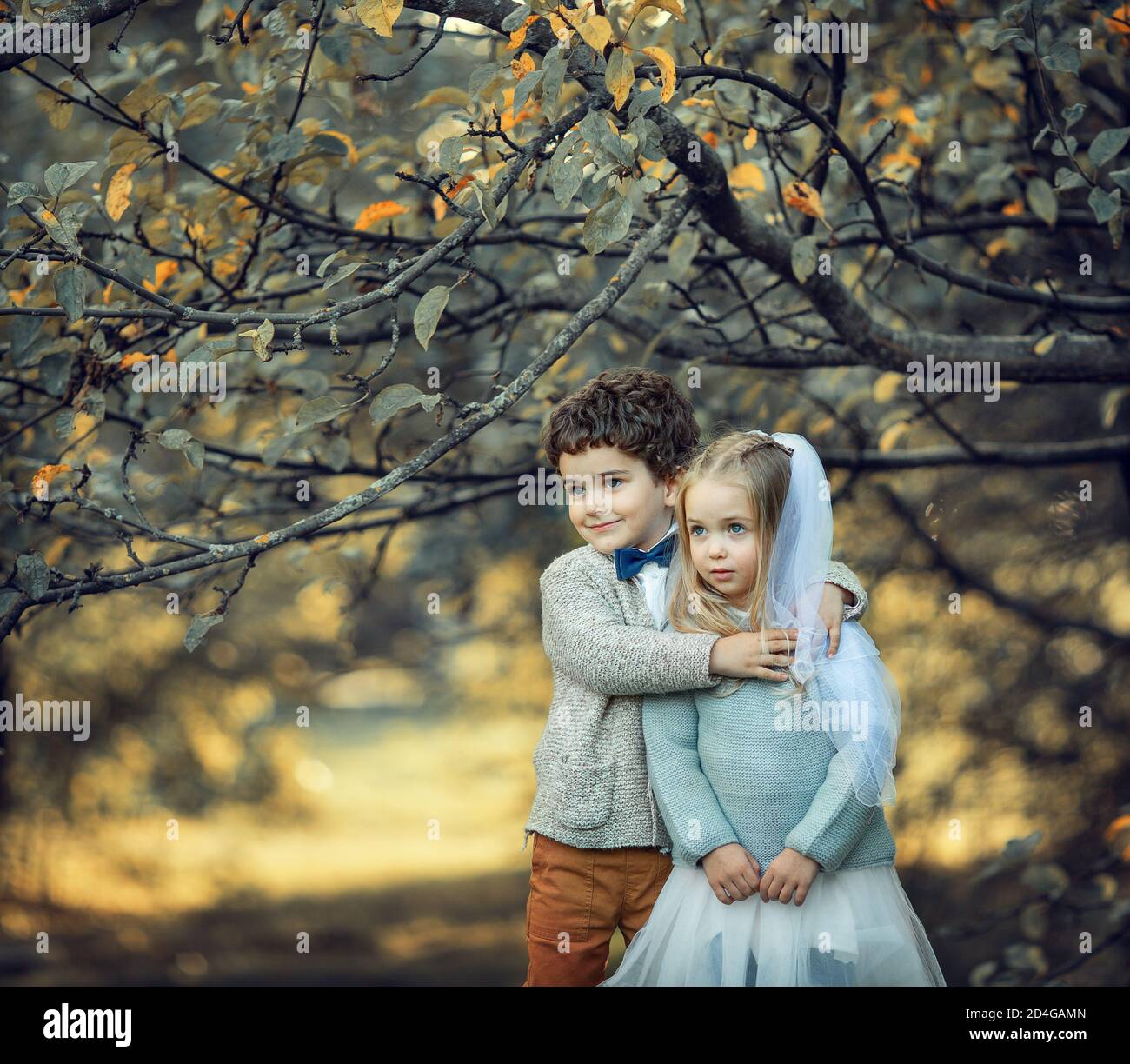boy and girl dressed as bride and groom stand under an apple tree Stock ...