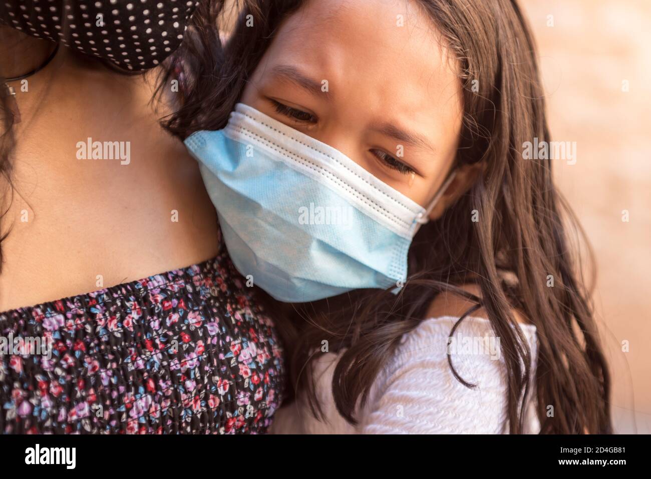 Closeup shot of a little girl in tears wearing a facial mask during the ...