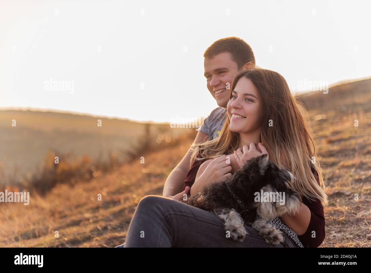 Young family with a schnauzer dog travel. Beautiful Girl hugs a young ...