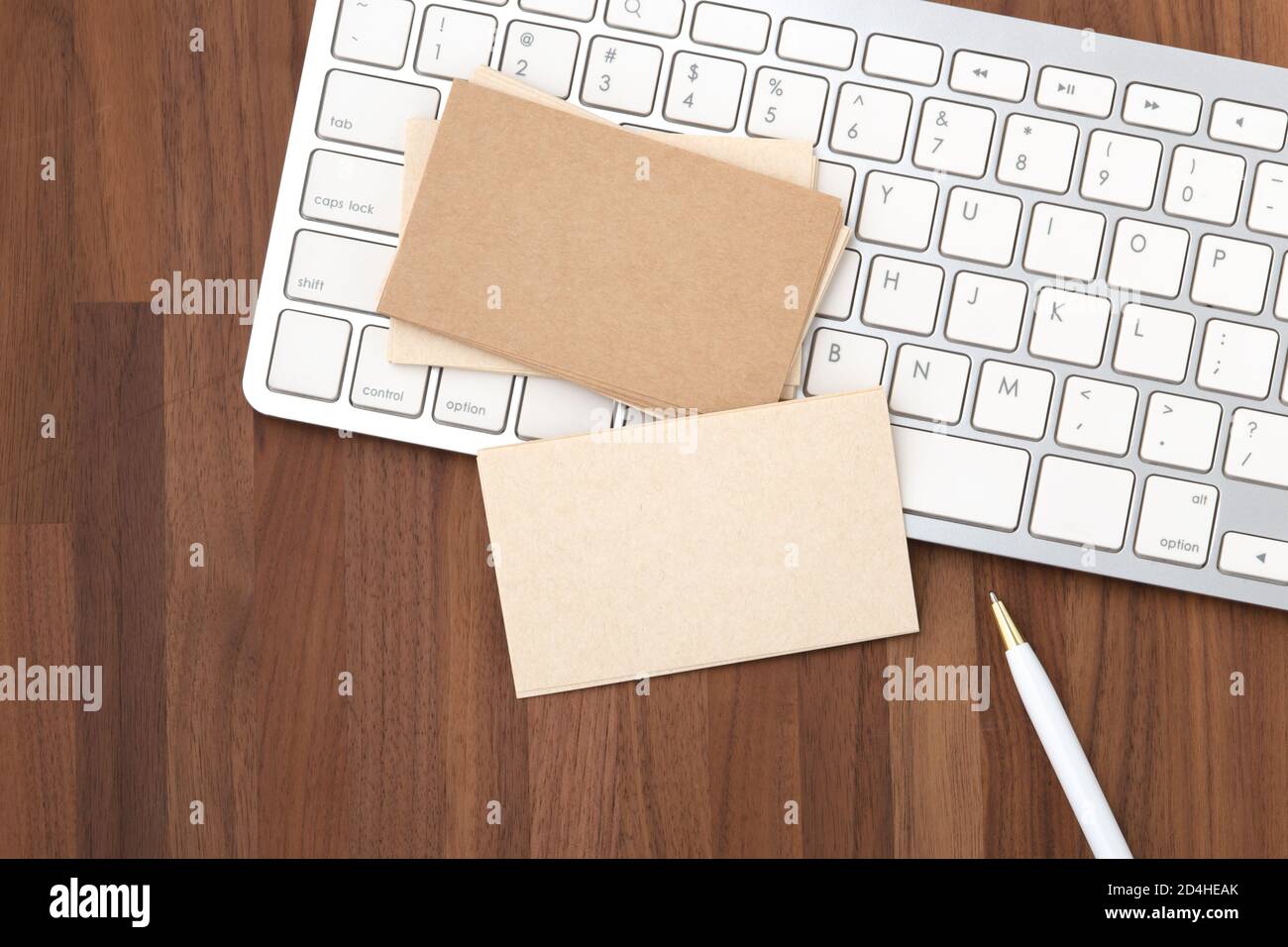 Business card on computer keyboard on wooden office table, top view ...