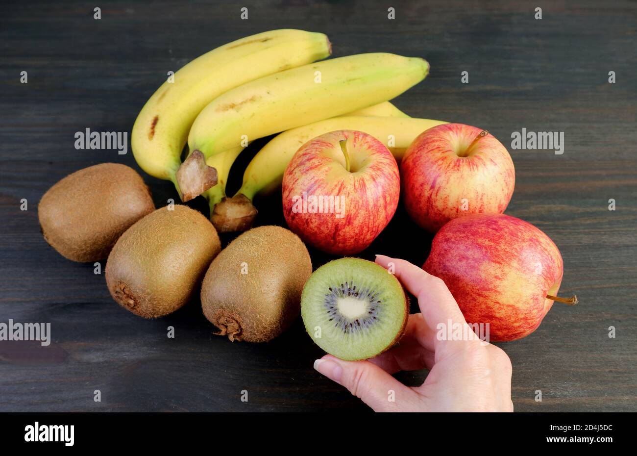 Assorted Fresh Ripe Fruits on Black Wooden Background with Hand Holding ...