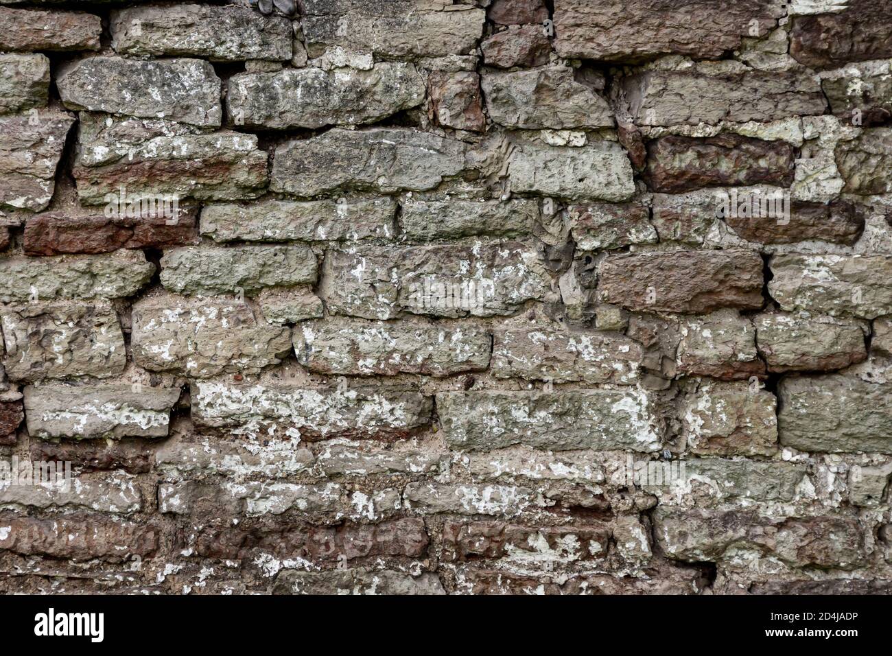 The surface of an old stone wall, masonry of uneven wild hewn stones ...