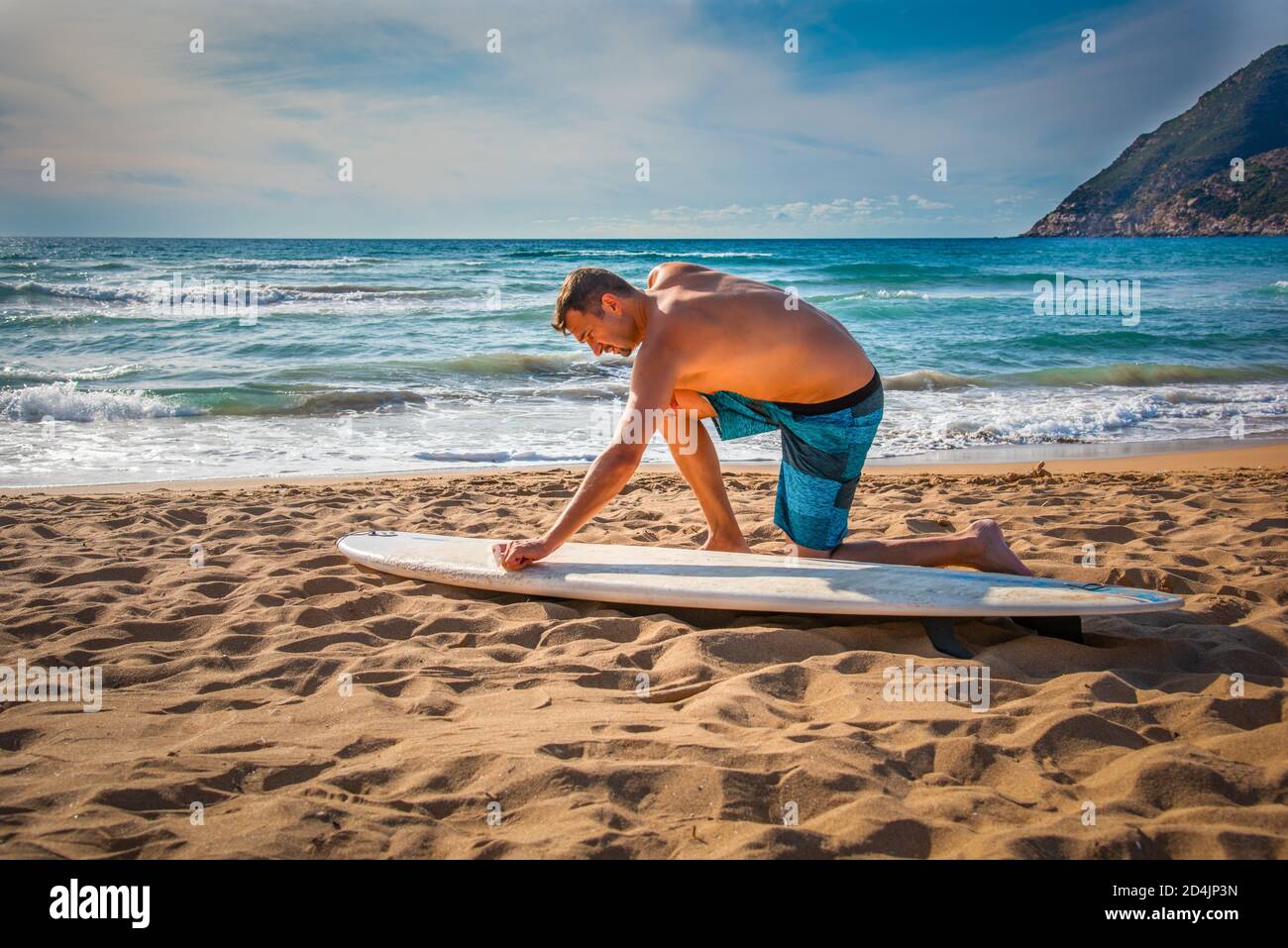 Man waxing a surfboard on the sand before the surf session Stock Photo ...