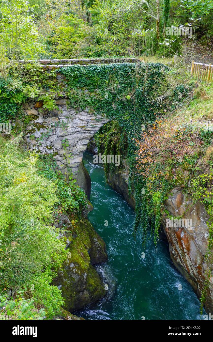 Vicdessos river in granite gorge, with old ivy covered bridge Auzat ...