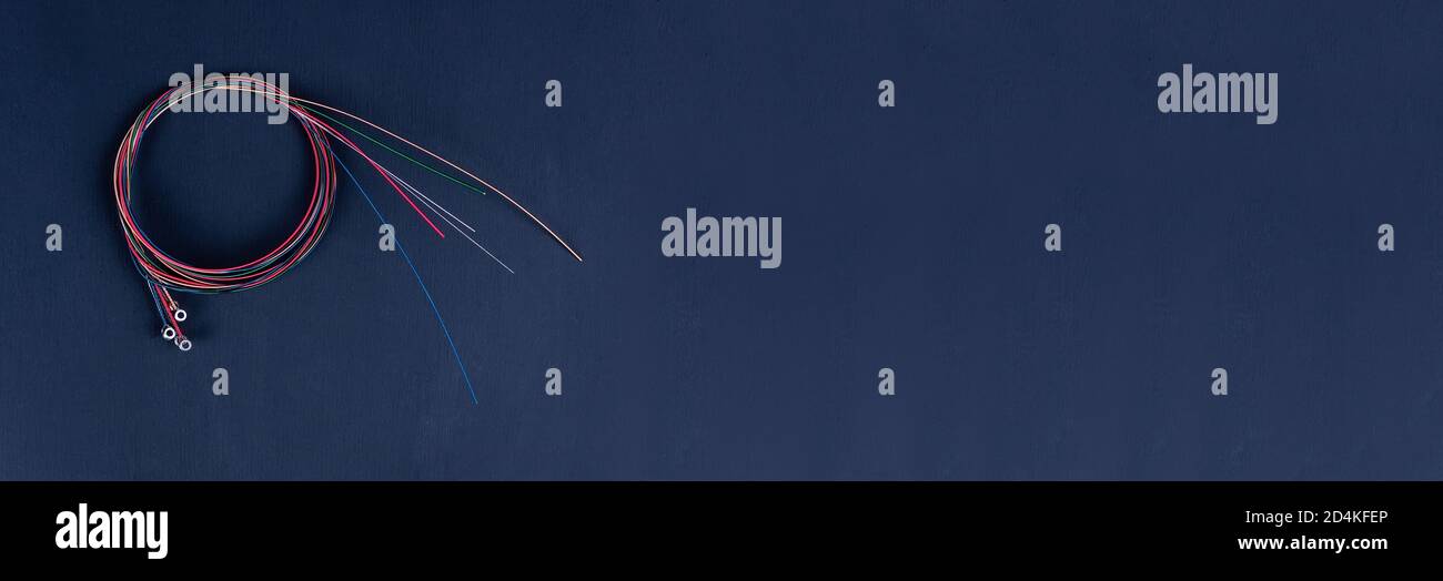 set of six coiled acoustic guitar strings randomly placed against black ...