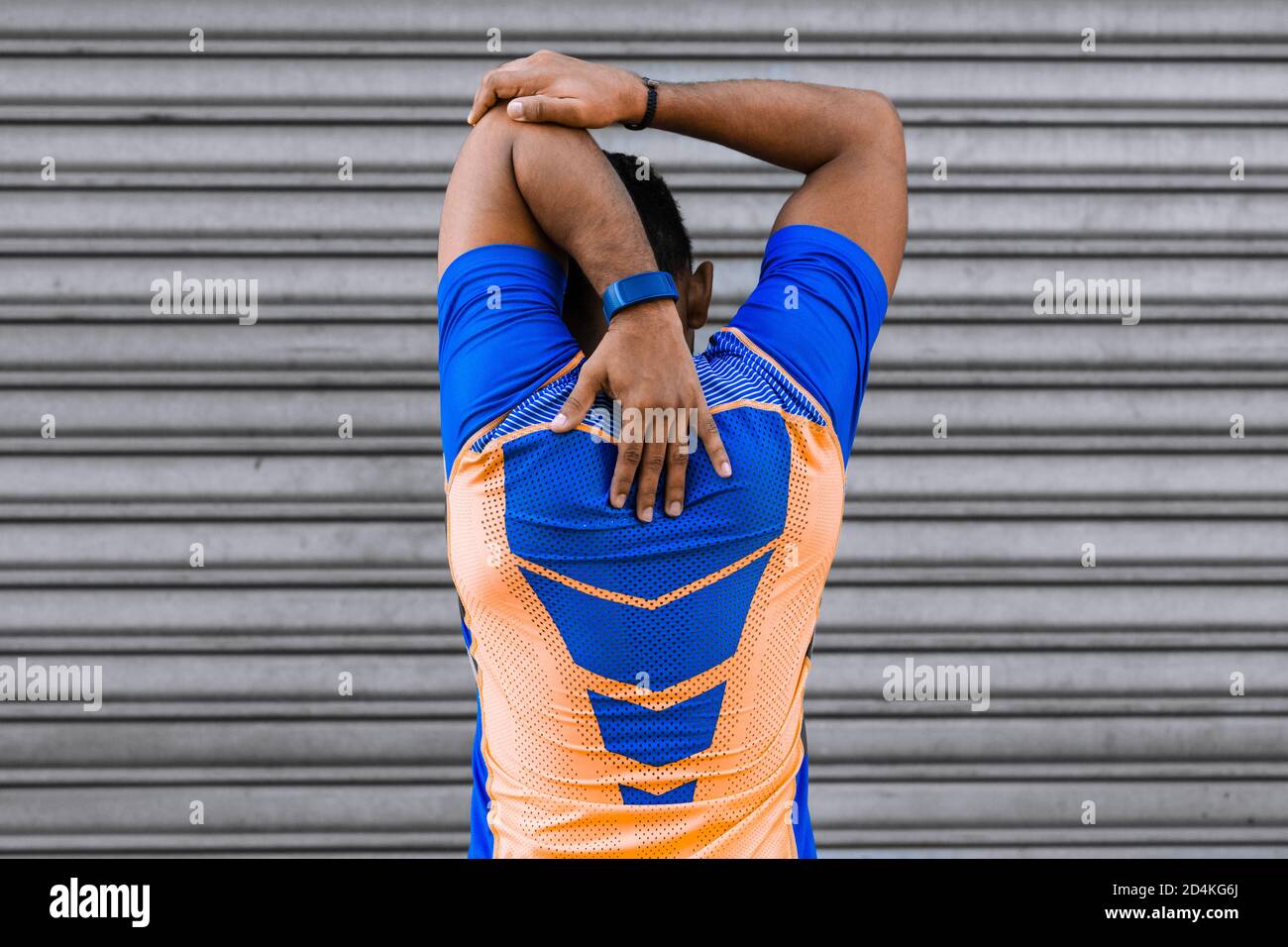Back view of a young hispanic male doing arm exercises in front of a ...