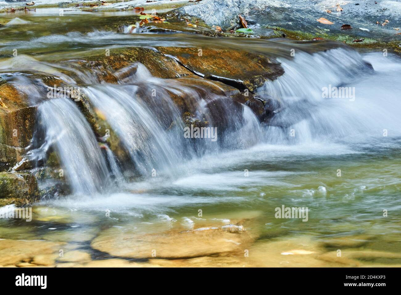 clear stream flows over the stones, forming a small waterfall, water ...