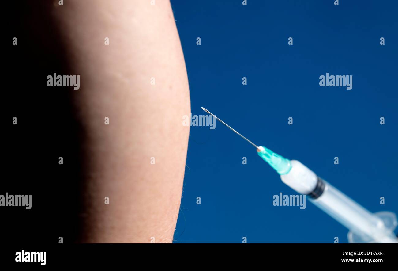 Closed syringe isolated on blue background, with man's arm Stock Photo ...