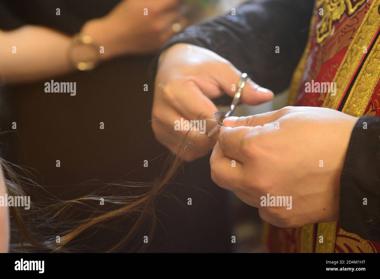 Orthodox baptism - the priest cutting a lock of hair of the child being ...