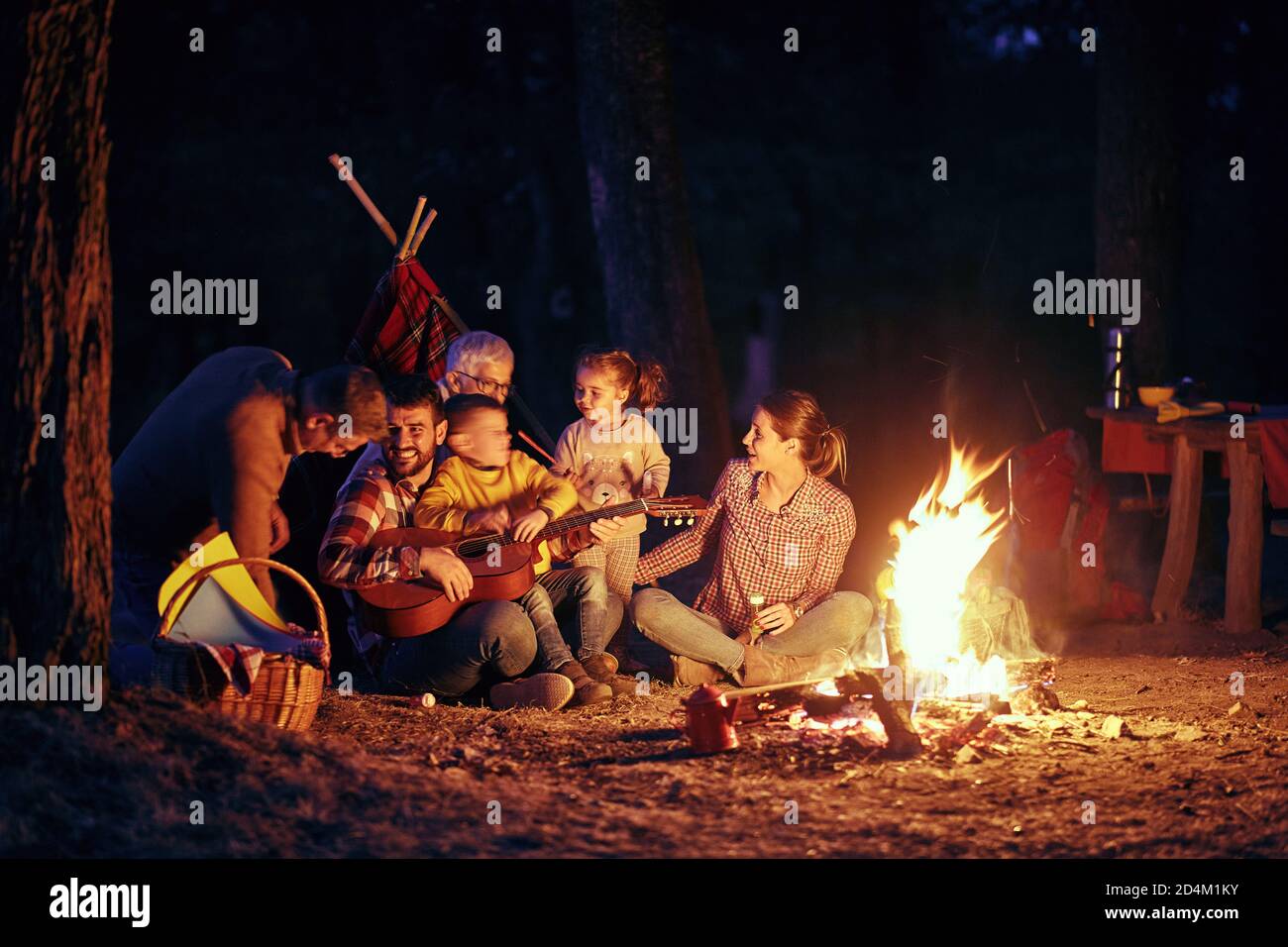 A happy family having a good time around a campfire in the forest in a ...