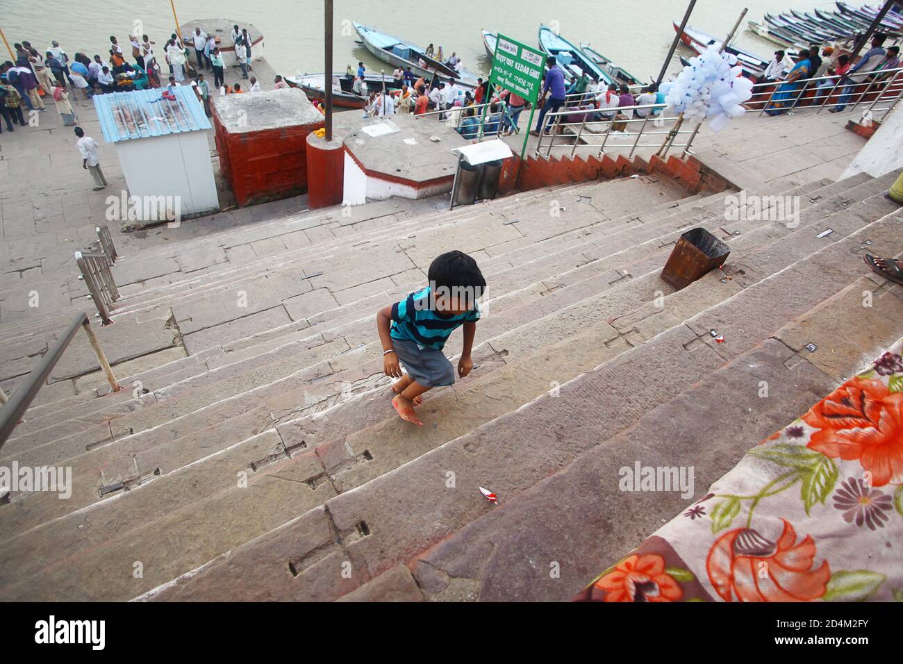 A boy climbs the stairs of the temple by the Ganges river. In Varanas ...