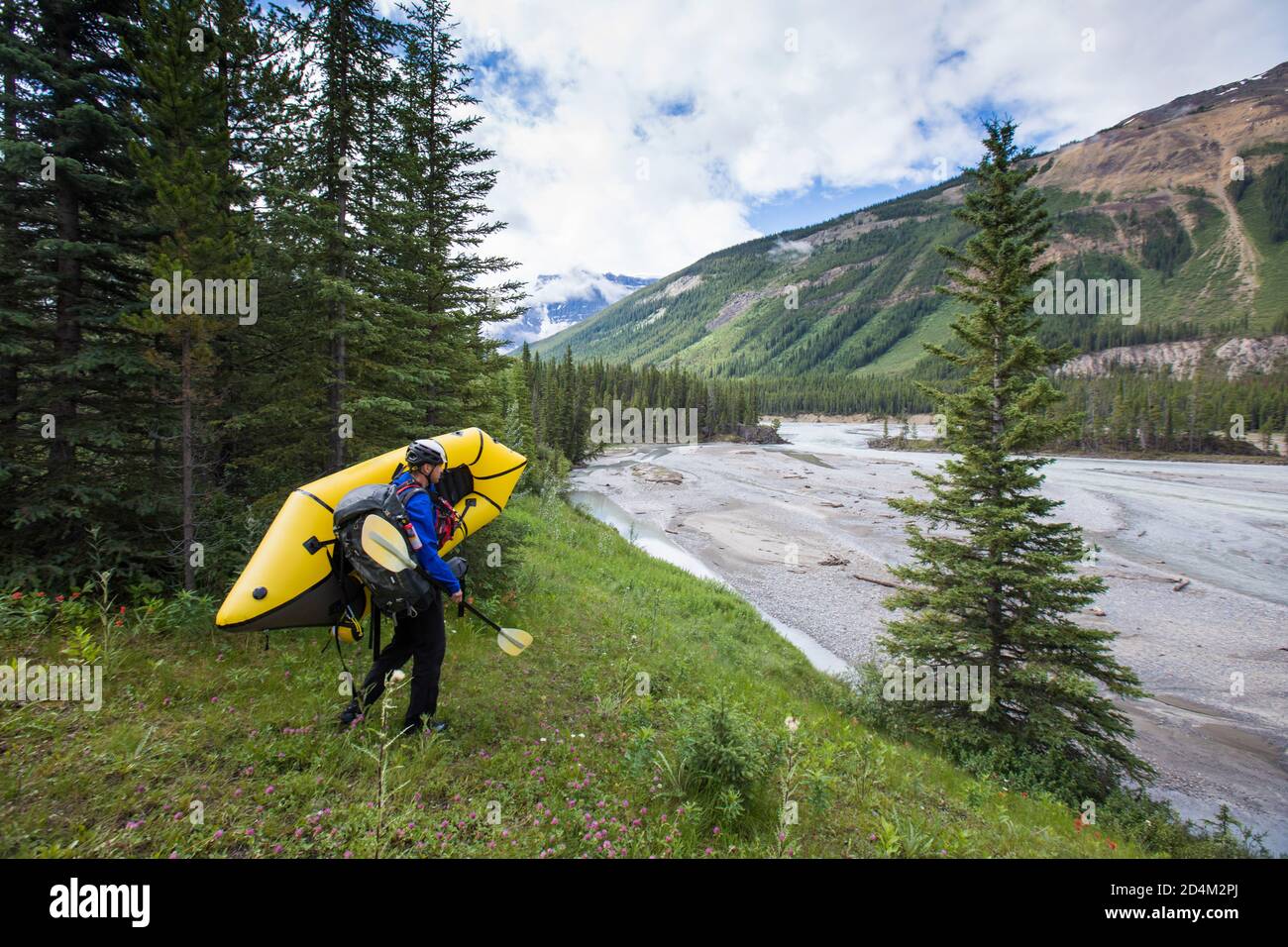 Explorer carries inflatable boat down to river in Banff National Park ...