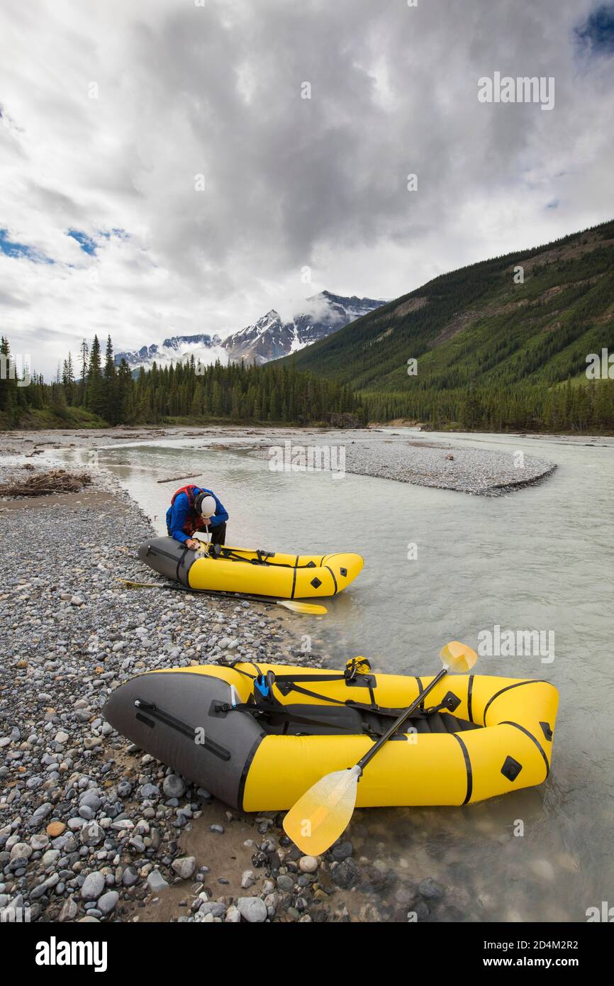 Adventurous man inflating packrafts in the rocky mountains Stock Photo ...