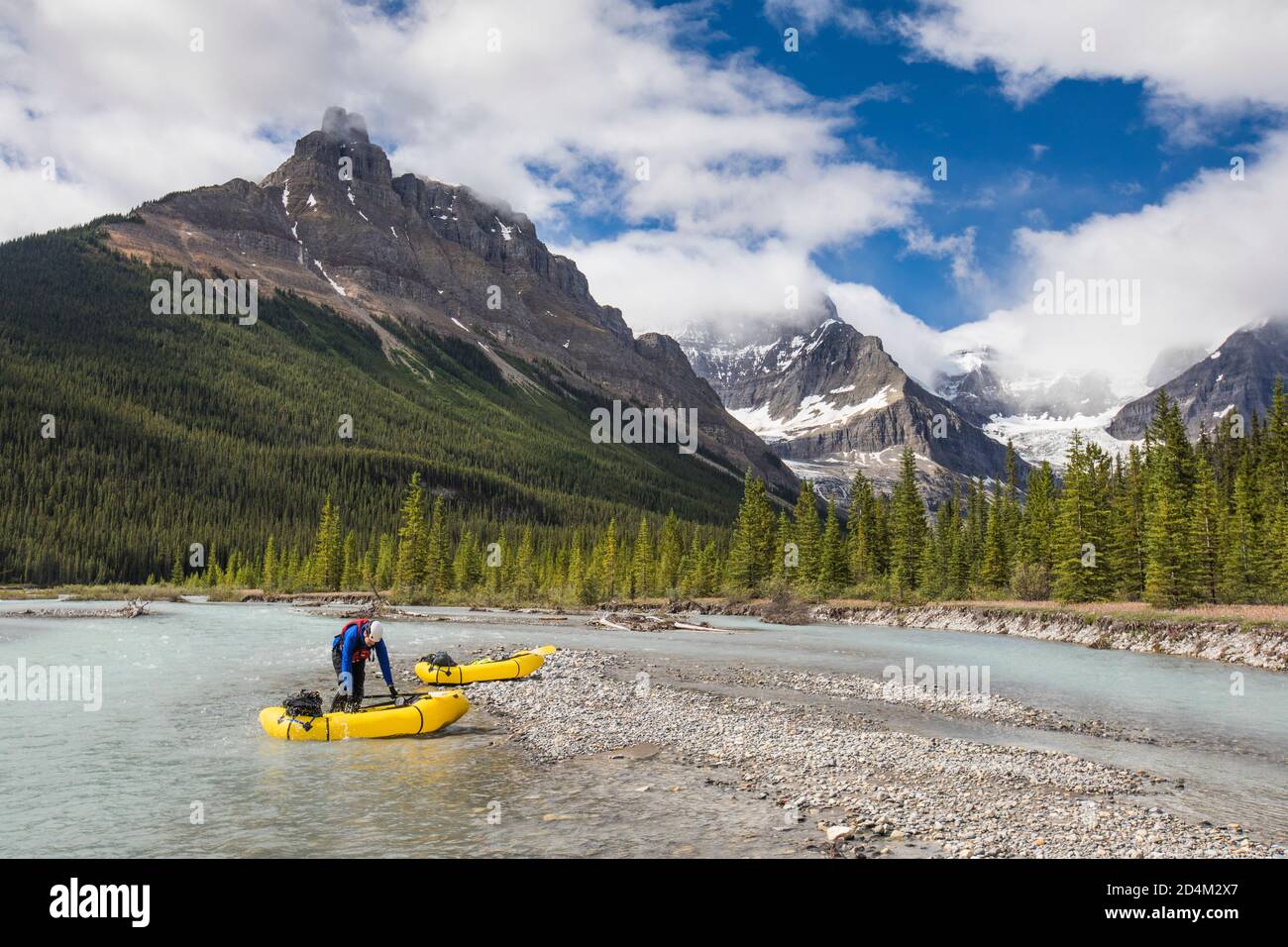 Paddler prepares to launch yellow inflatable raft into scenic river ...