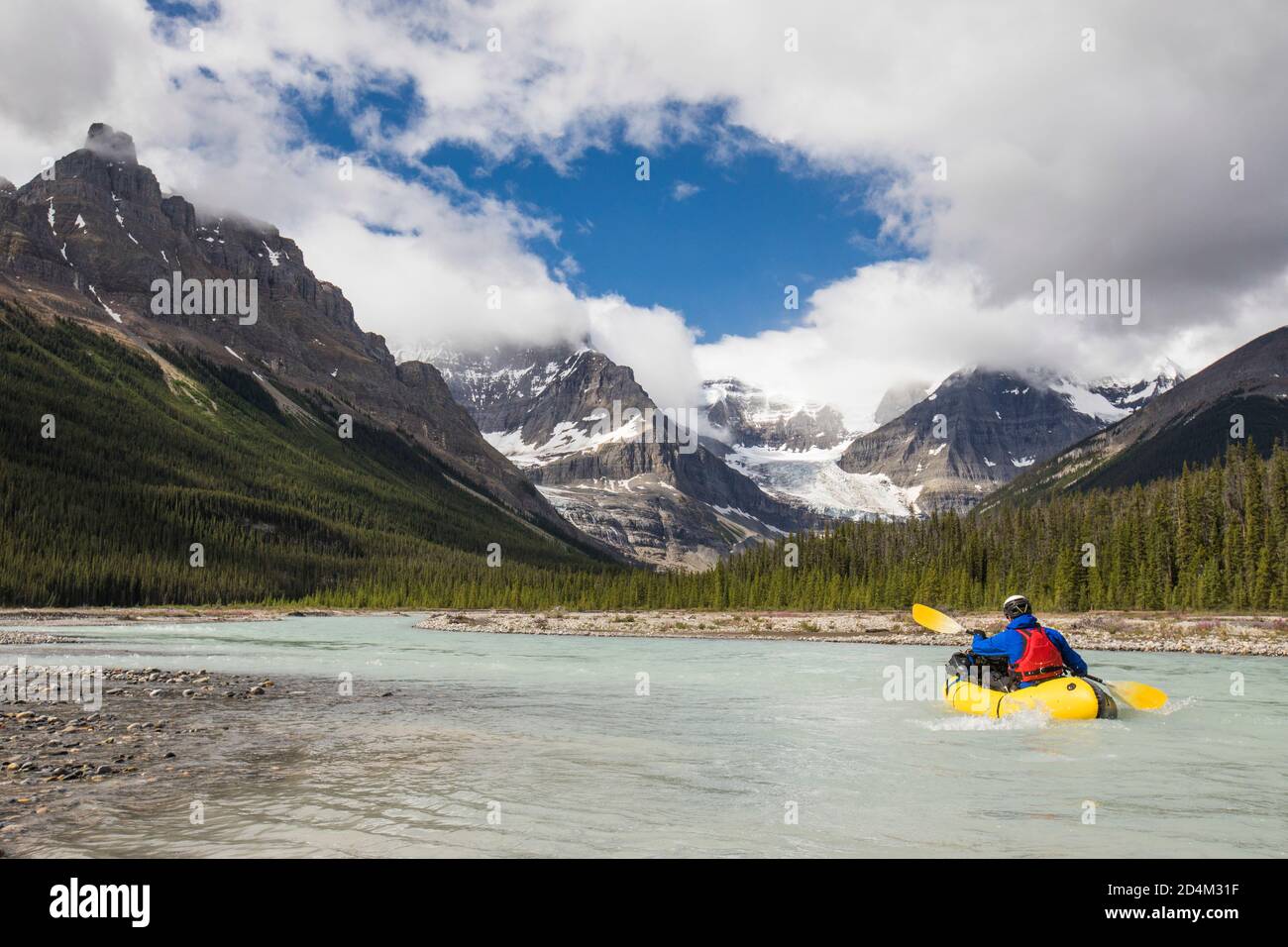 Explorer paddles yellow raft towards the Rocky Mountains, Banff Stock ...