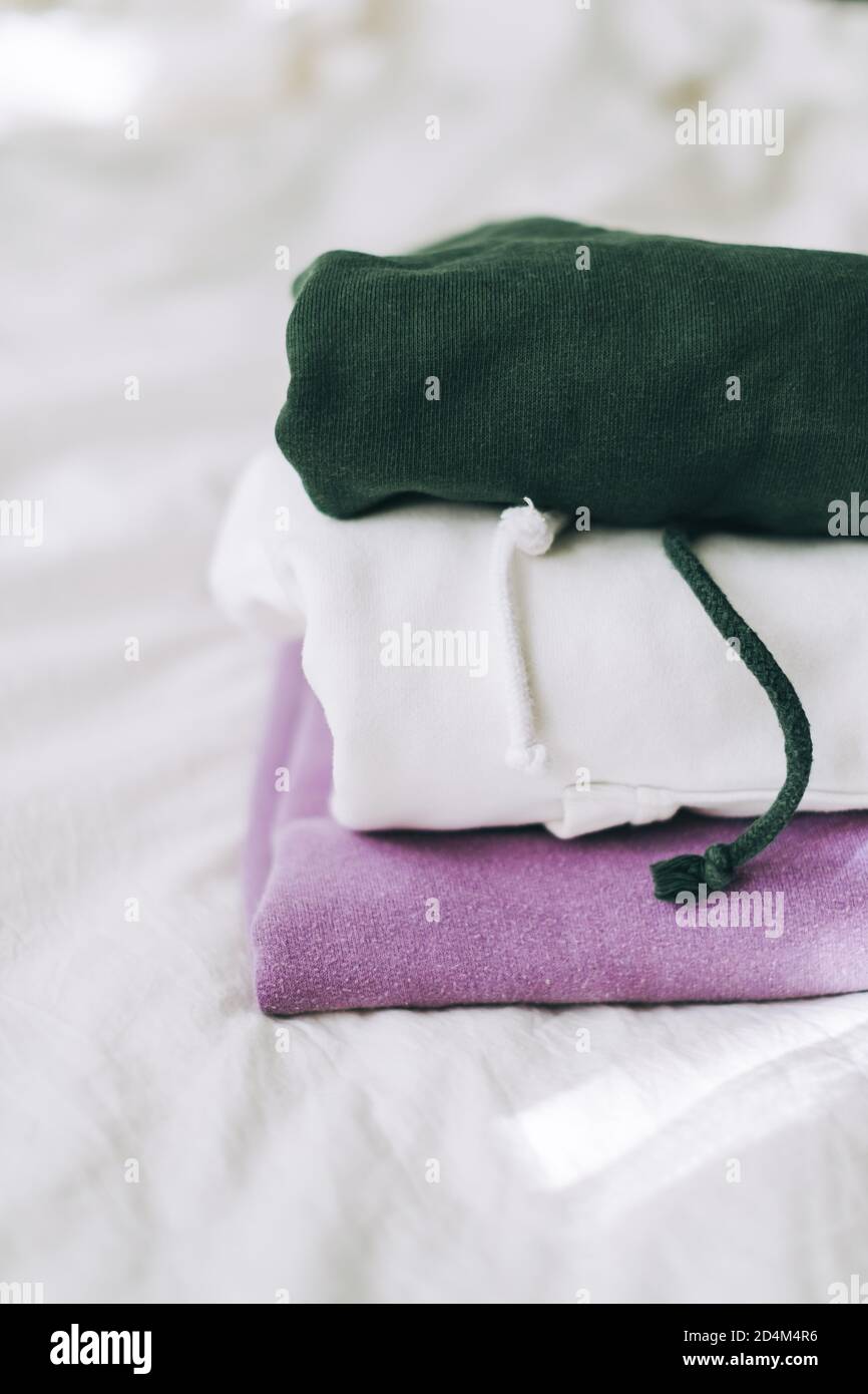 Stack of multicolored clothes on a white bed from wardrobe Stock Photo ...