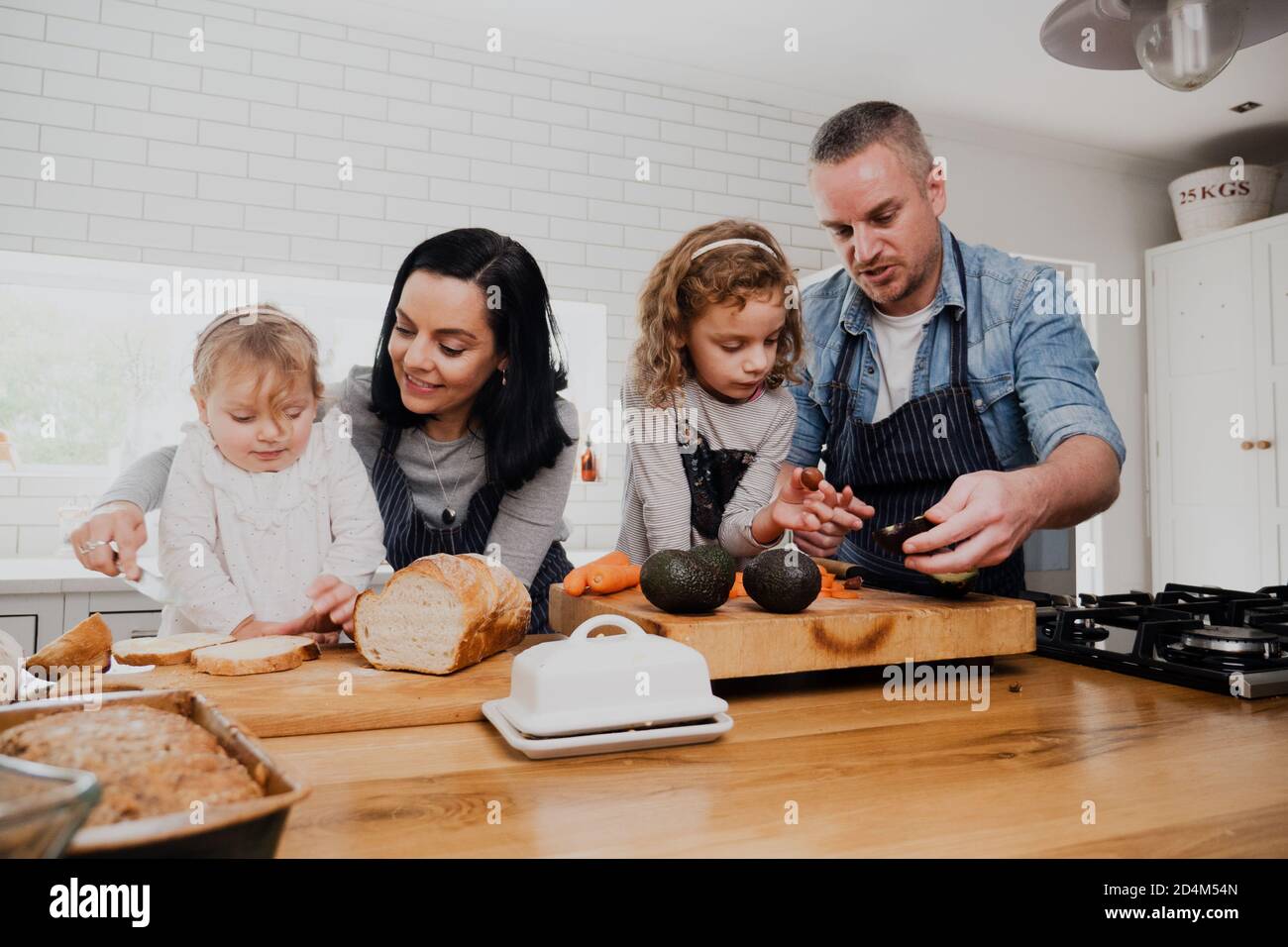 Young caucasian family cooking together, sisters and parents having fun ...