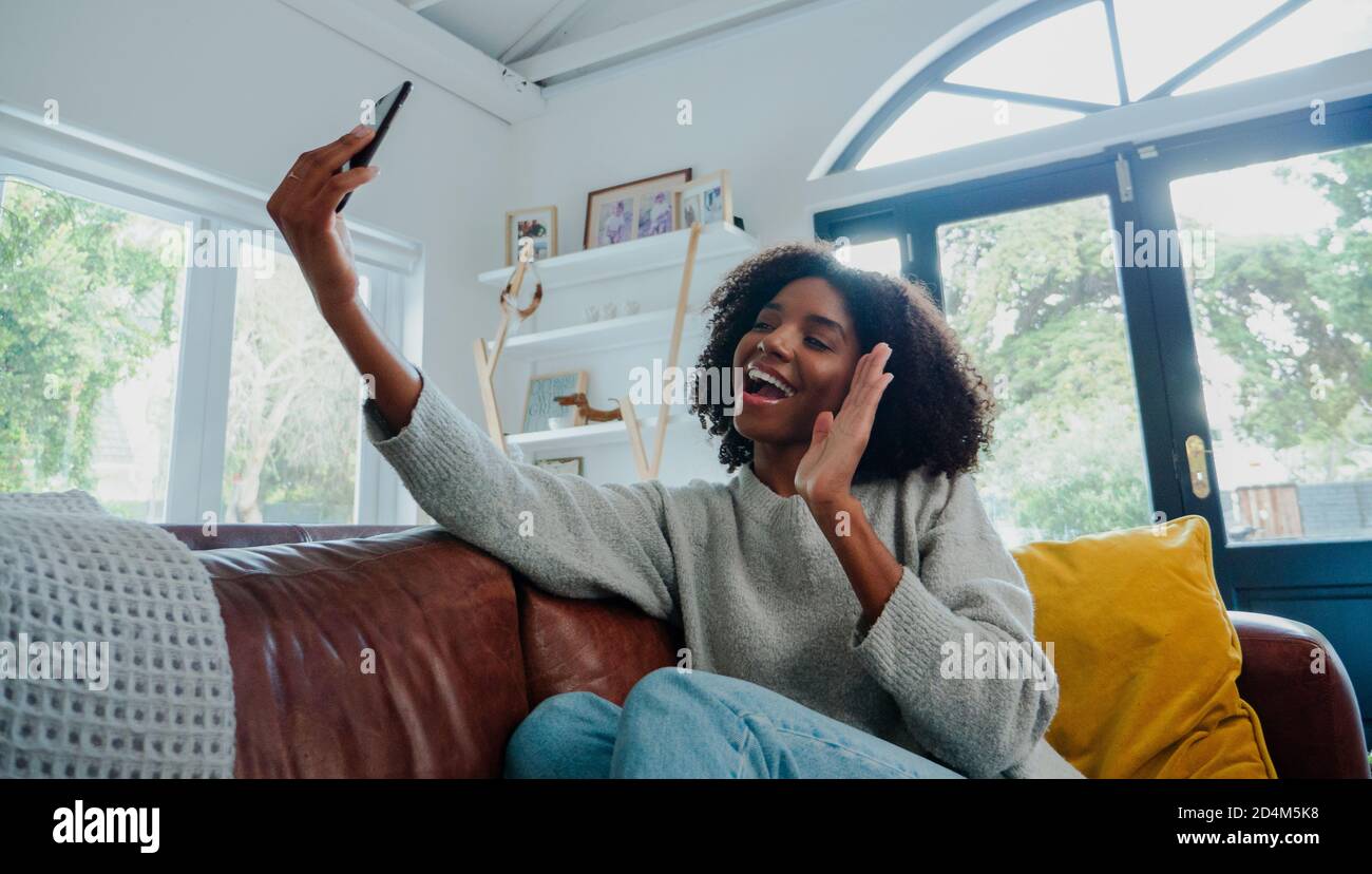 Beautiful woman video calling friend on mobile device at home Stock ...