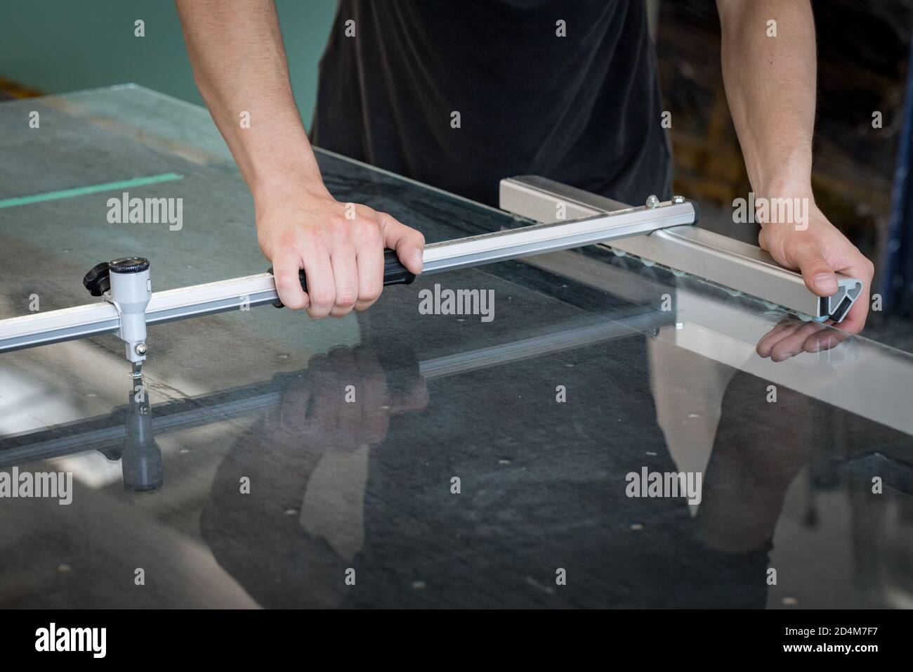 A man cuts the glass with the help of specialized tools in a glass ...