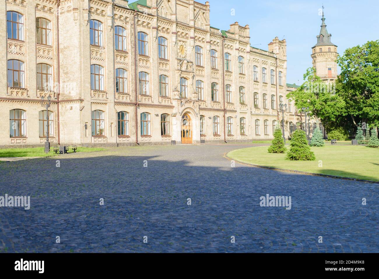 Photo image of old styled university building with green park at ...