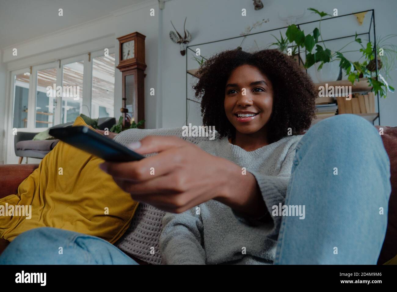 Young female switching channels with tv remote control Stock Photo - Alamy